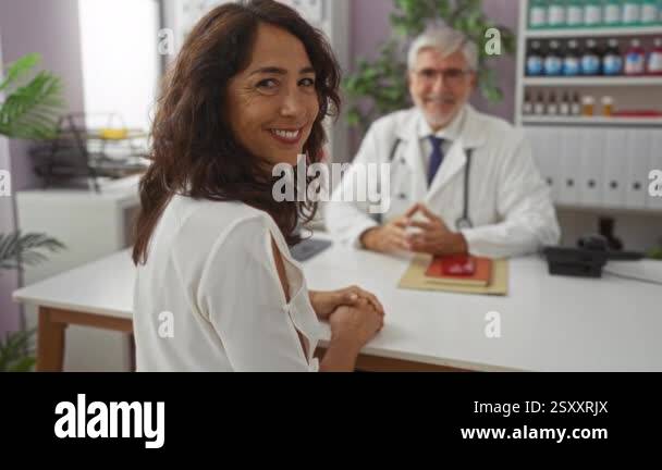 Woman smiling at doctor in healthcare room, medical consultation in hospital setting, focus on ...