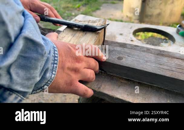 Construction worker removing nails from wooden plank using crowbar and ...