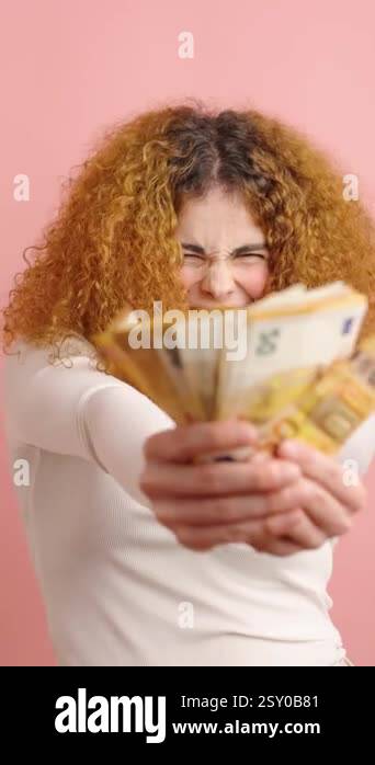 Young cheerful woman displaying banknotes, radiating excitement with ...