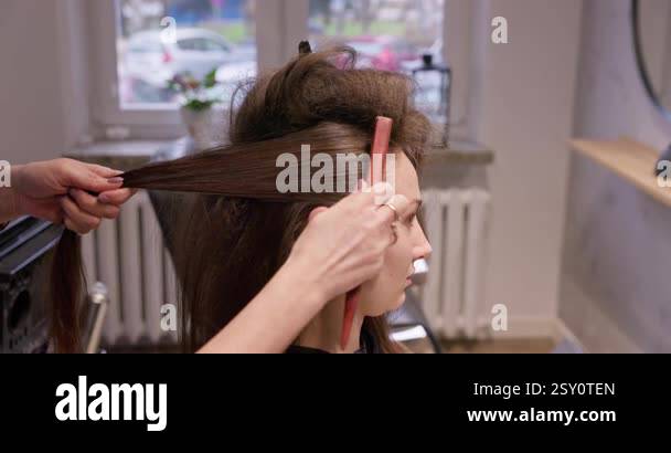 A stylist is meticulously working on hair while showcasing an ...