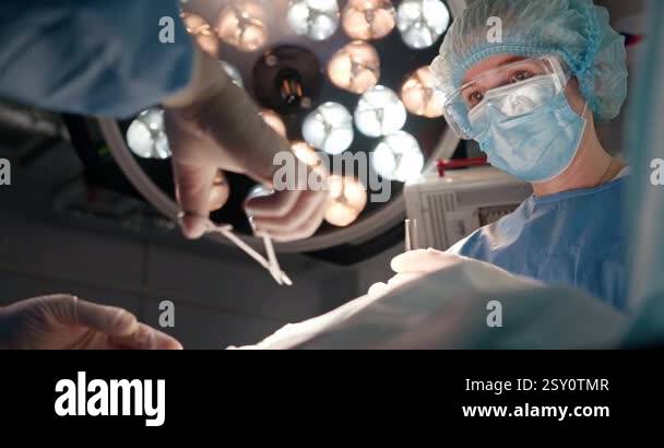 Female surgeon focusing on surgery in modern hospital operating room ...