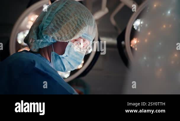 Surgeon wearing scrubs and mask during operation. Intense concentration ...