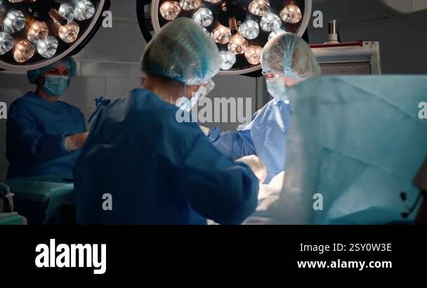 Medical professionals wearing sterile scrubs engaged in surgical ...