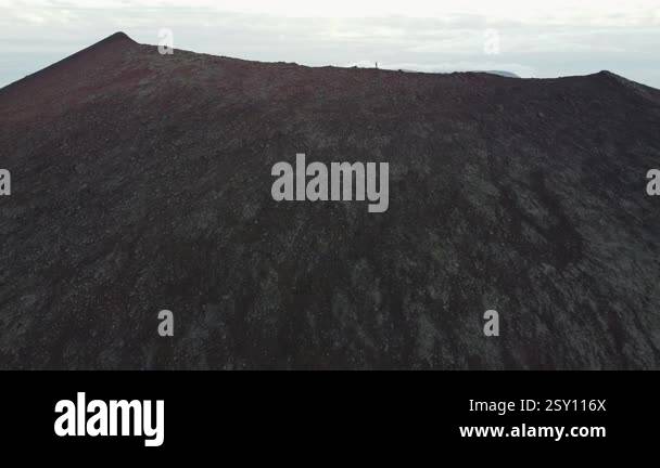 Explorer stands on the summit of an extinct volcano, gazing into a ...