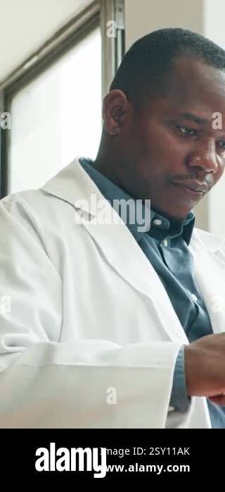 A serious African American medical doctor reviews patient information ...