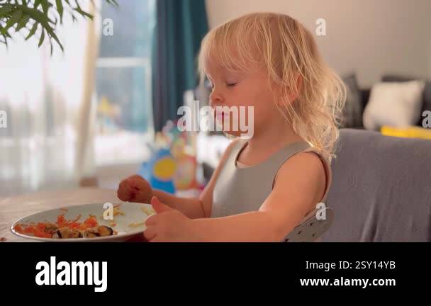 A young child is enthusiastically engaging with their meal at a dining ...