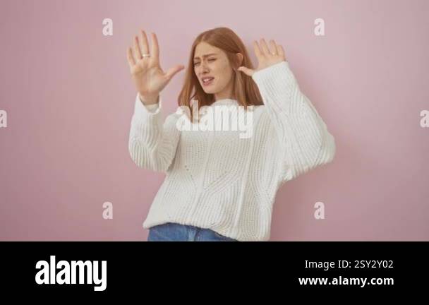 Terrified young redhead woman in sweater yelling in fear and shock ...