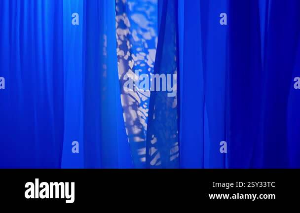 Windows with colorful tulle fabrics blown by the wind. Transparent silk ...