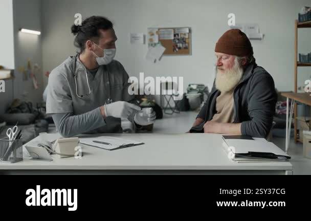 Medium pan shot of young Caucasian male doctor in medical uniform, face ...