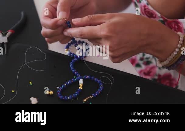 A small business owner designing and crafting unique handmade jewelry ...