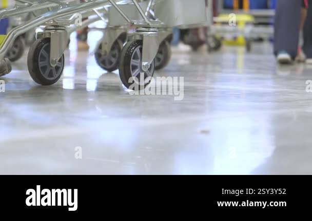 Close-up view of shopping cart wheels and peoples feet navigating the ...