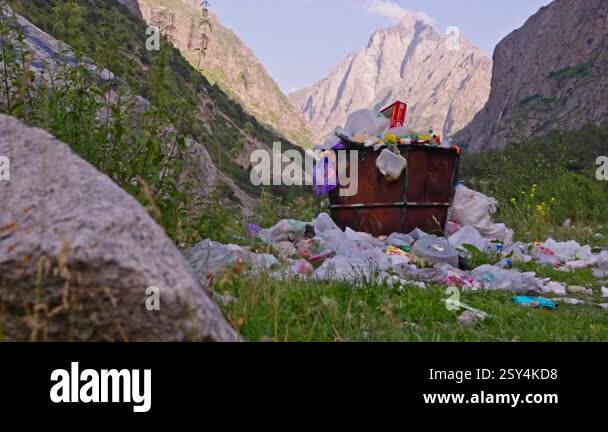 Overfilled garbage bin with trash around in the mountains at summer ...
