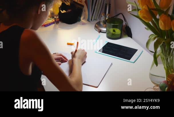 Female student holds pen firmly and begins writing in paper notebook ...