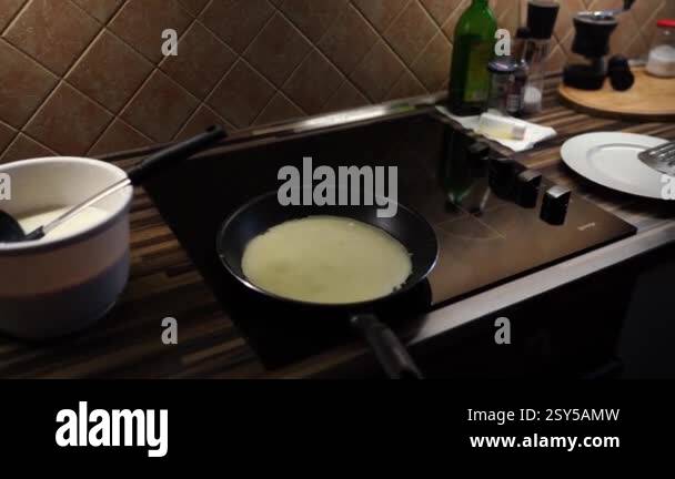 Thin pancake is baked in a frying pan on the stove. High quality 4k ...