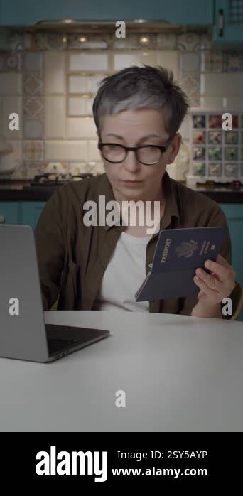 A mature woman completes an online form while holding a US passport at ...