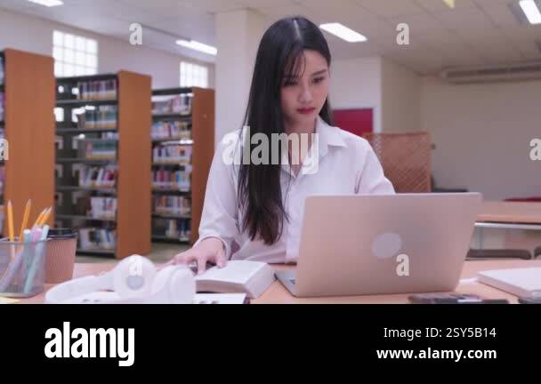 Young Asian female university students are earnestly completing their assignments on their ...