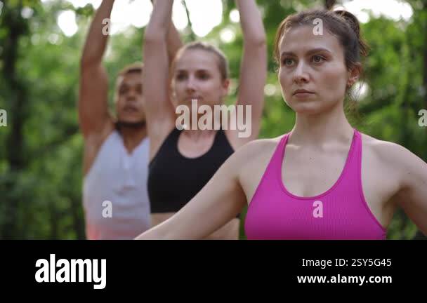 Three individuals are engaged in yoga poses outdoors, skillfully ...