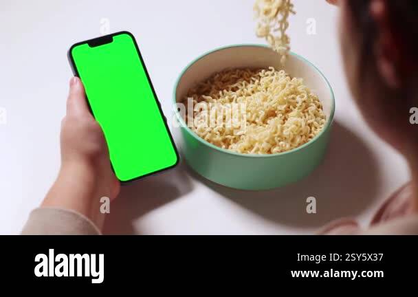 Female using smartphone while eating pasta at home. Smartphone with ...