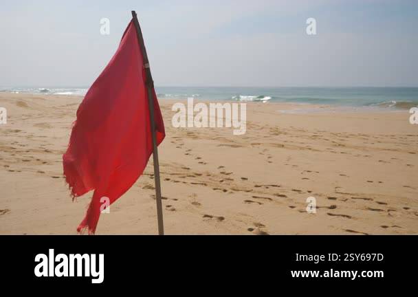 Close up of red flag as warning sign on the sandy beach before storm at ...