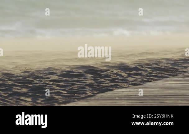 Powerful wind blowing sand particles across wooden boardwalk, creating ...