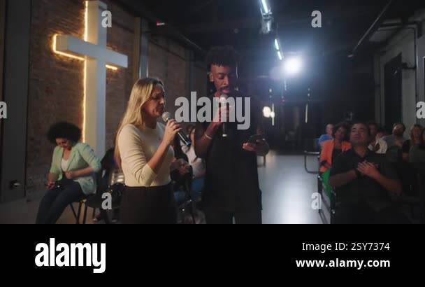 Man and woman singing together with microphones during worship ...