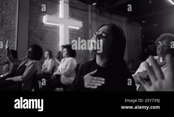 Young woman singing in prayer during worship service, hand on chest in ...