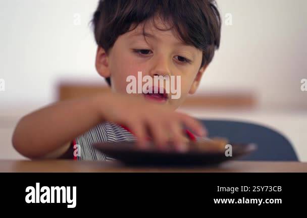 Young boy eating snack, enjoying bite of cookie, playful expression ...