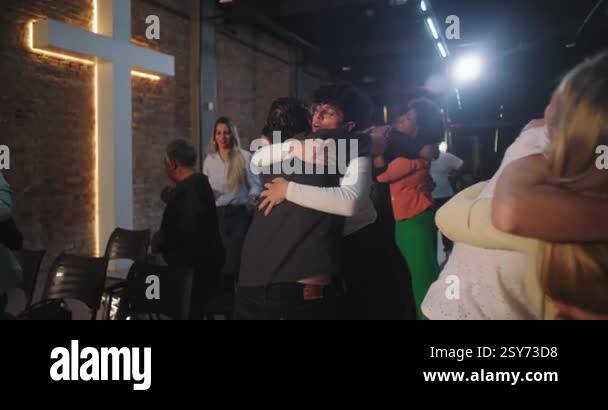 People embracing each other in church after service, illuminated cross ...