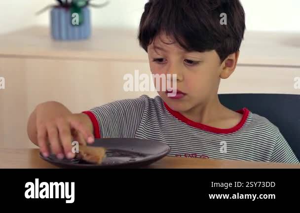 Boy eating snack, enjoying bite of bread, relaxed expression, casual ...