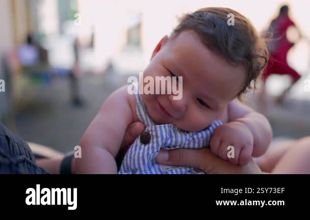 Close-up of baby being held in mothers arms, smiling with bright ...