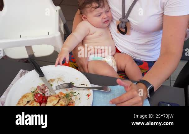 Mother holding sleeping baby during lunchtime, tender moment of ...