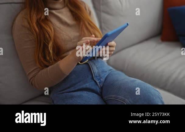 Woman using tablet on sofa at home shows casual indoor lifestyle with a ...