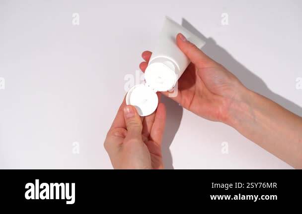 Female hands open white mockup tube of cream lotion and apply it on ...