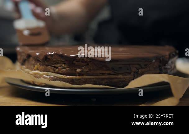 Chocolate glaze is poured over a cake base - closeup. High quality 4k ...