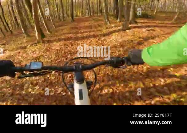 POV: Riding an electric bicycle along a leaf covered forest trail on a sunny afternoon in autumn ...