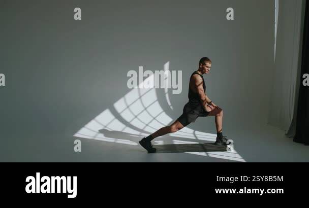 Man with an athletic build performs physical exercises in a well-lit ...