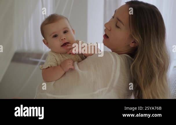 Young woman holding her little daughter and playing with her. Adorable ...