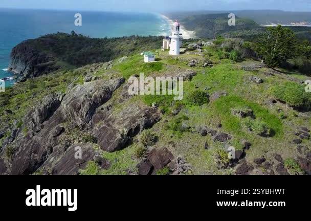Aerial view of a white lighthouse on a grassy hill by the Australian ...