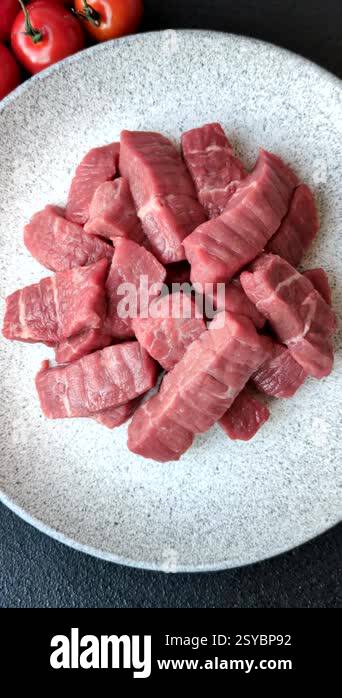 Raw beef tenderloin cut into slices with salt and spices on a dark ...