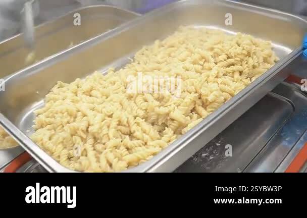 Chefs distribute hot cooked pasta into trays for serving Stock Video ...