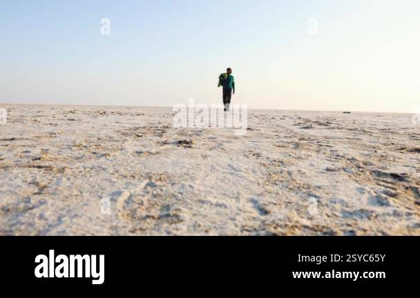young man walking at white salt desert with bright blue sky at morning ...