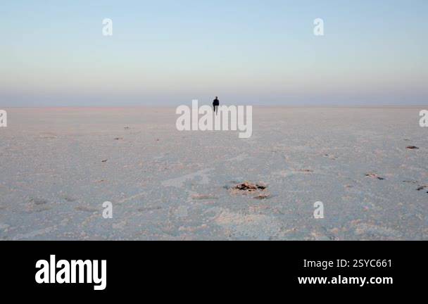 young man running at white salt desert with bright blue sky at morning ...