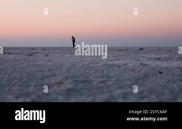 isolated man using mobile at remote white salt desert with bright ...