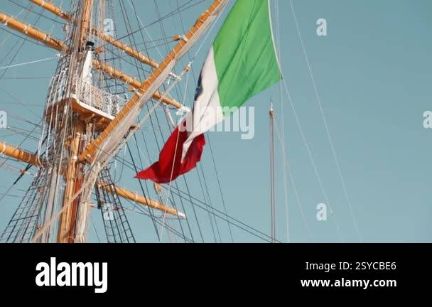 naval ensign of Italy on sailboat mast against blue sky, tradition ...