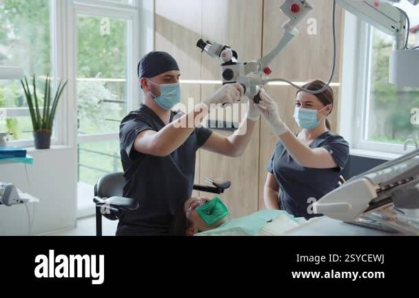 Dentist in blue medical uniform and mask using dental operating ...