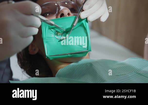 Close-up footage of woman wearing rubber dam in clinic. Dentist with ...