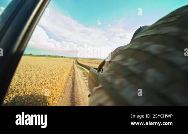 Close up soldier man running sitting in a car near a wheat field ...