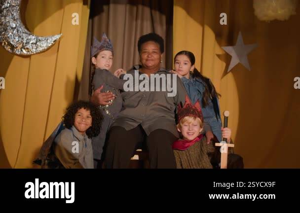 Medium long of senior theatre director and group of cheerful child ...