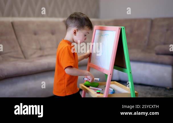 Adorable baby boy draws on the whiteboard with a blue marker. Toddler ...