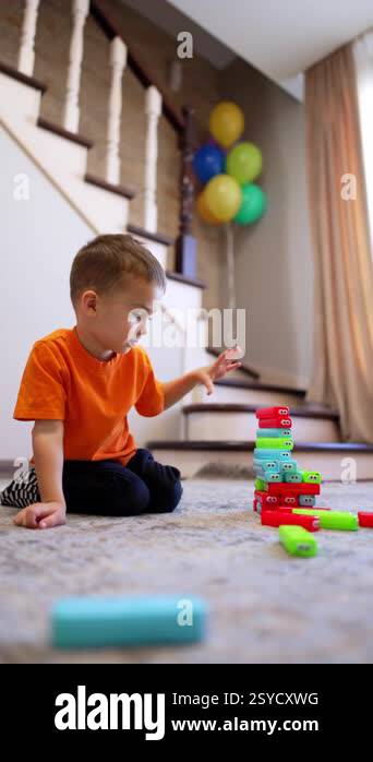 Caucasian kid sits on the floor playing with toys. Baby boy building a ...